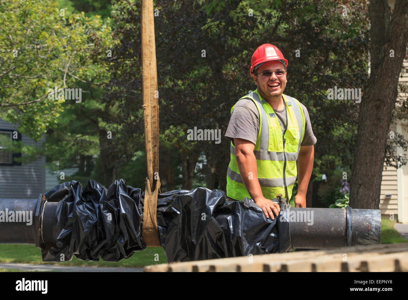 Construction worker guiding water main into place Stock Photo - Alamy
