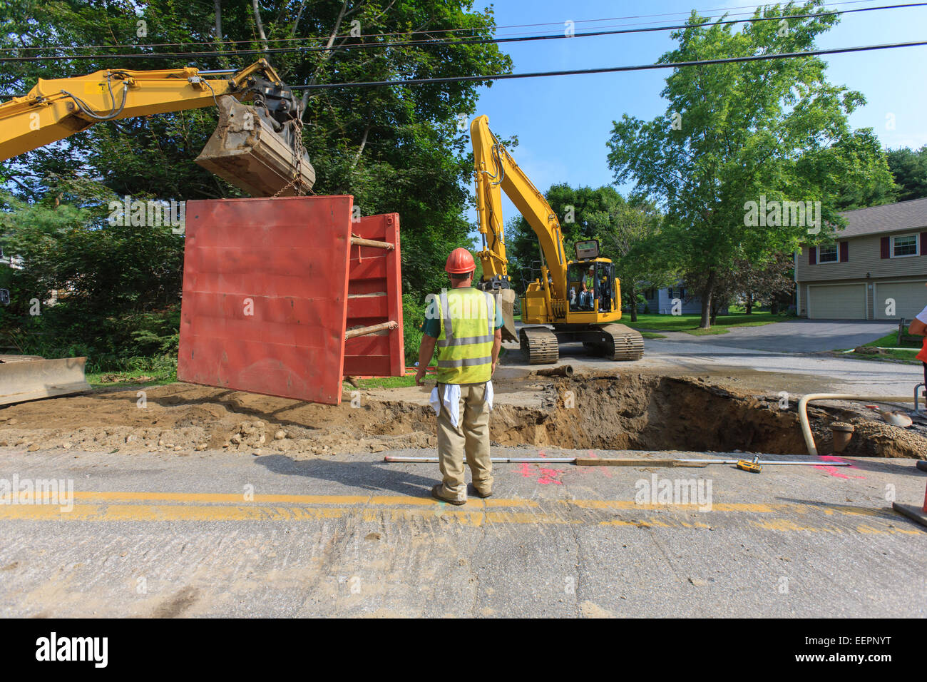 Construction worker watching excavator moving shoring to new section of ...