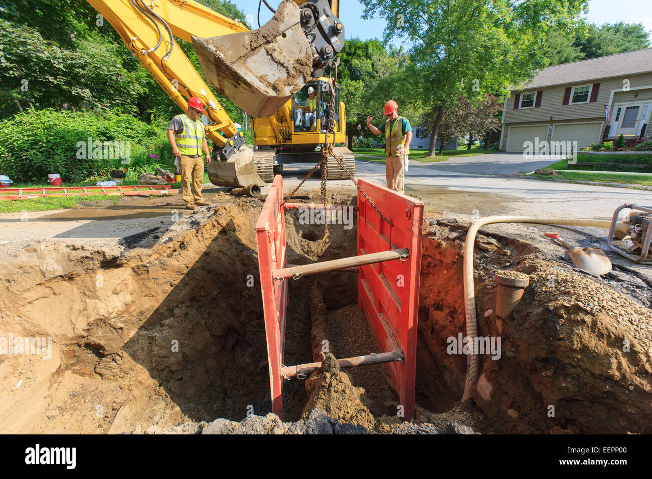Construction worker placing shoring into hole with excavator Stock ...