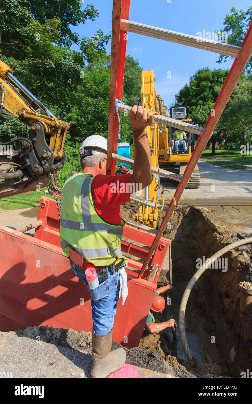 Construction worker entering shoring to inspect water main Stock Photo ...