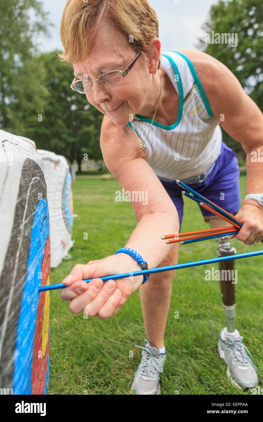 Woman with prosthetic leg pulling arrows from target after archery ...
