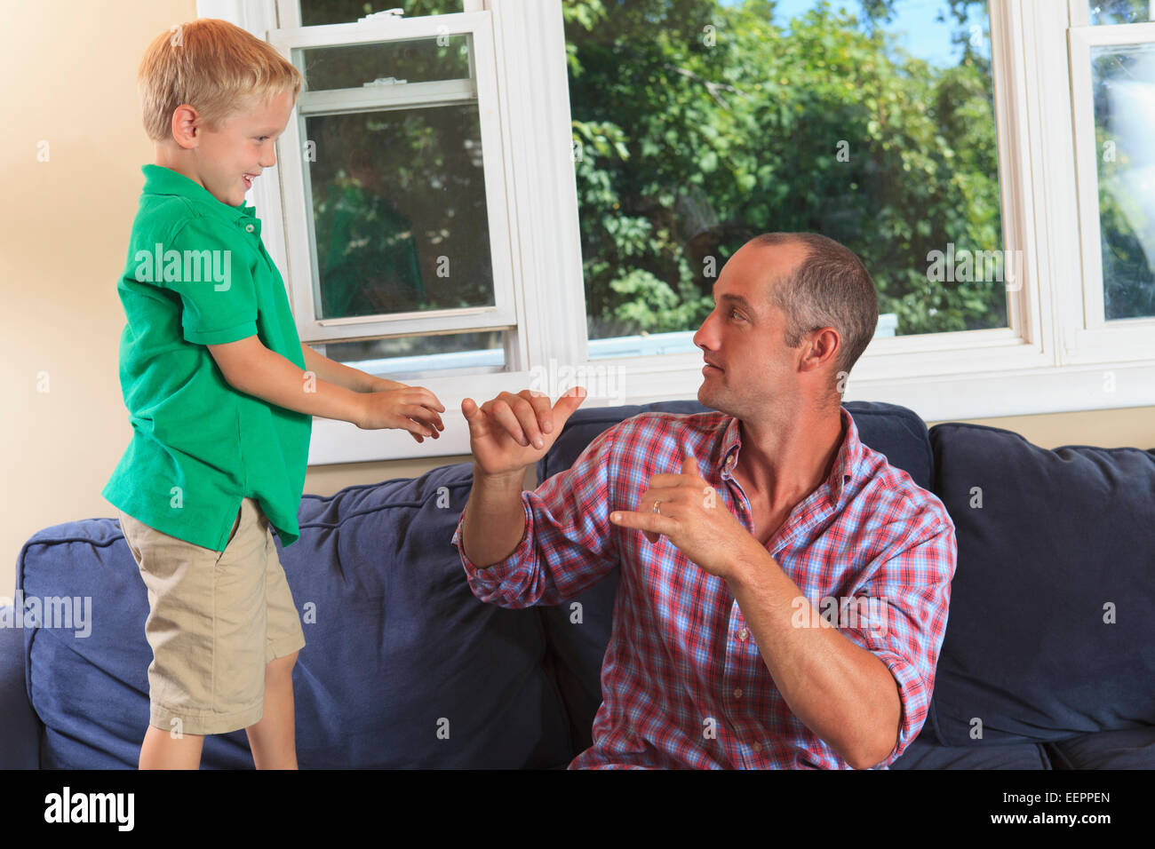 Father and son with hearing impairments signing 'play' in American sign ...