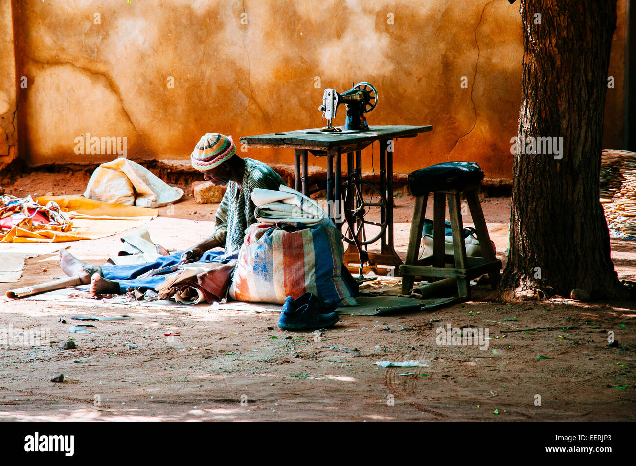 Tailor working on the floor under a big tree, Segou, Mali Stock Photo ...