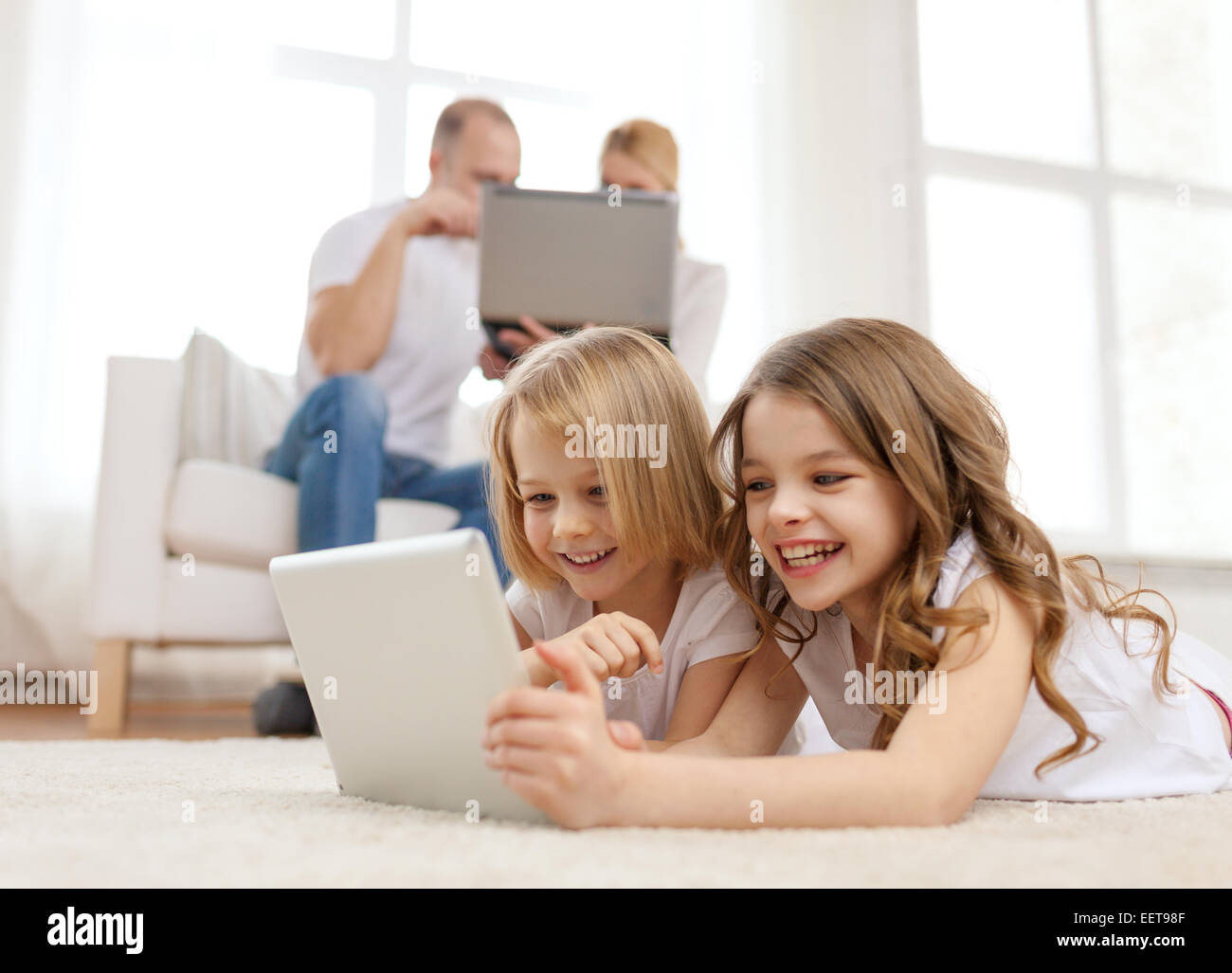 smiling sister with tablet pc and parents on back Stock Photo - Alamy