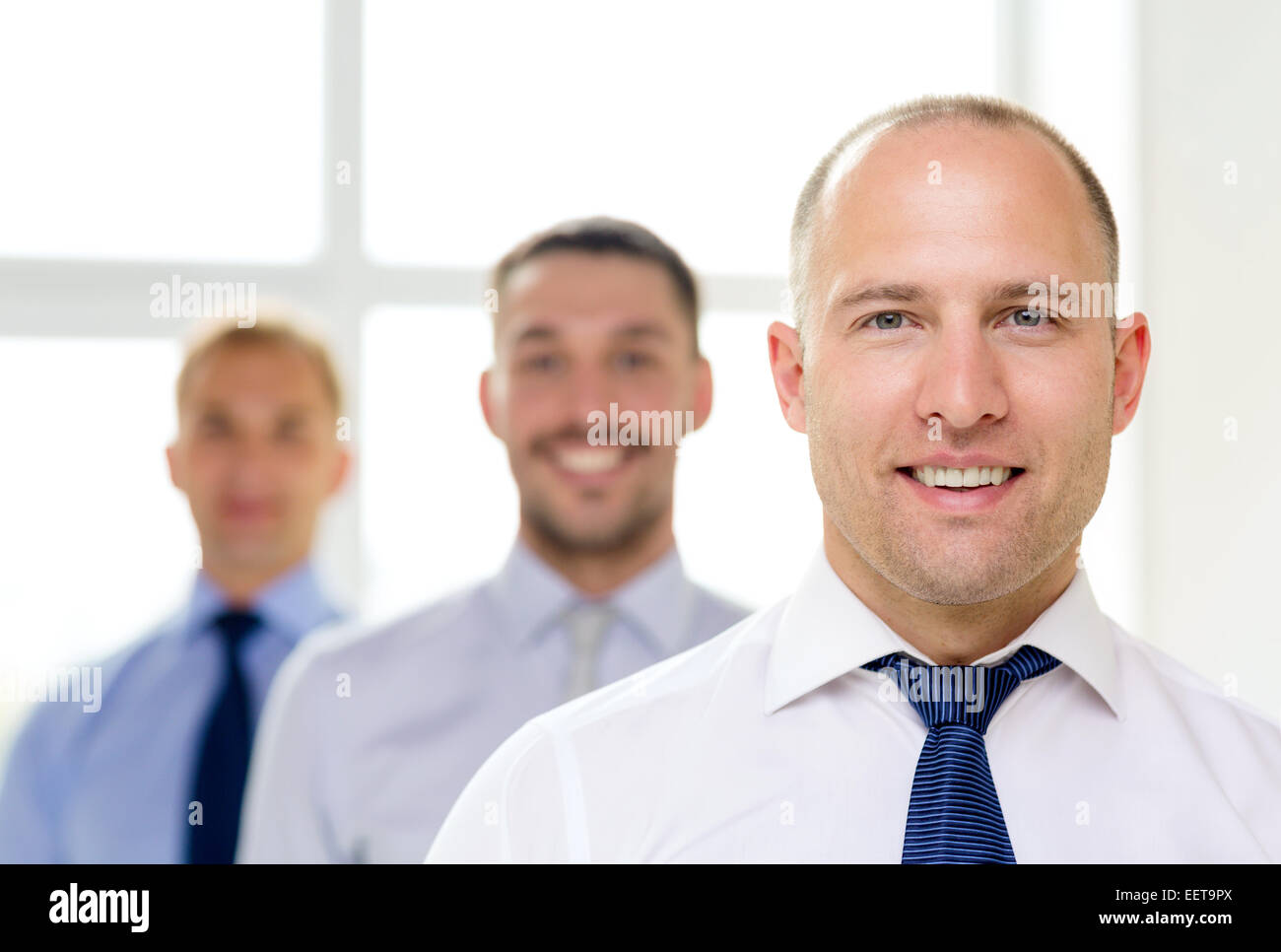 smiling businessman in office with team on back Stock Photo - Alamy