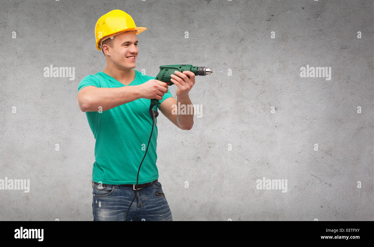 smiling manual worker in helmet with drill machine Stock Photo - Alamy