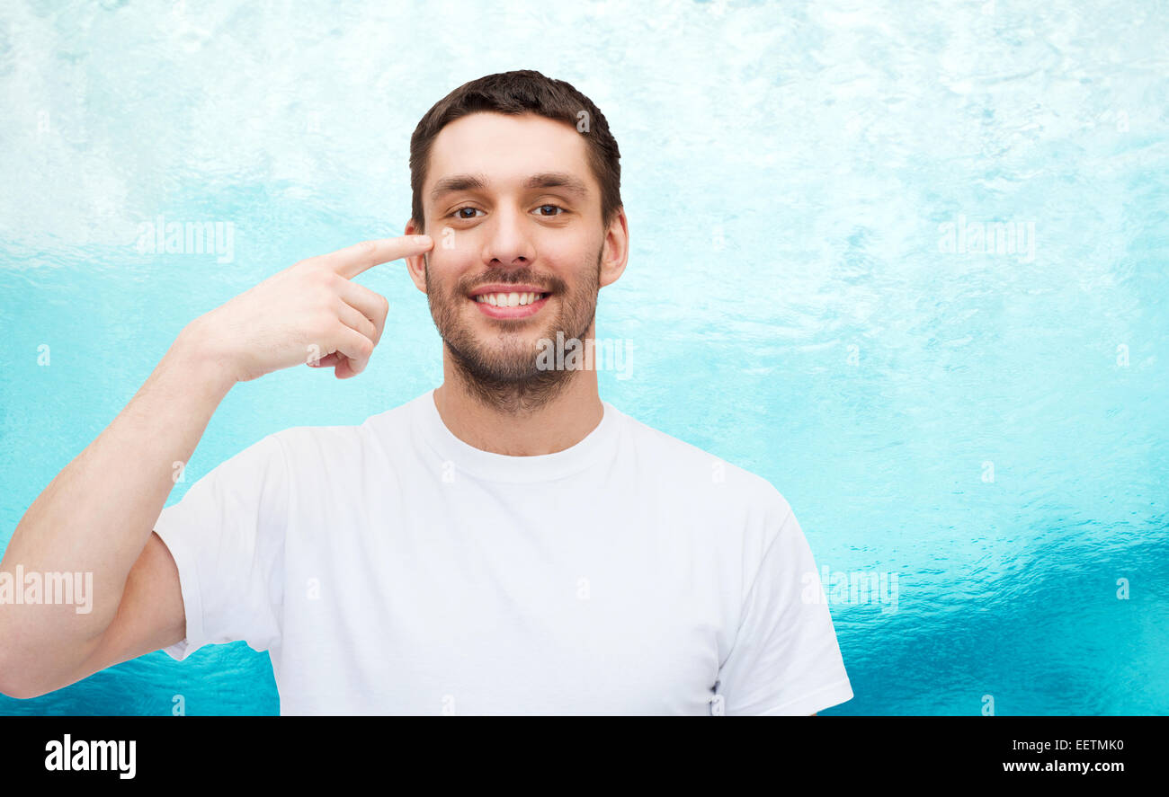 smiling young handsome man pointing to eyes Stock Photo - Alamy