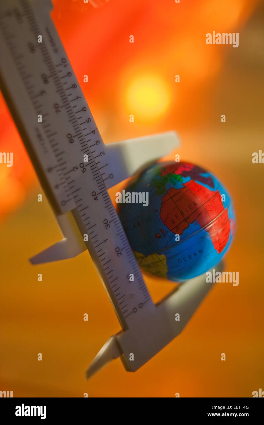 Small model of the world being measured by calipers illustrating a ...