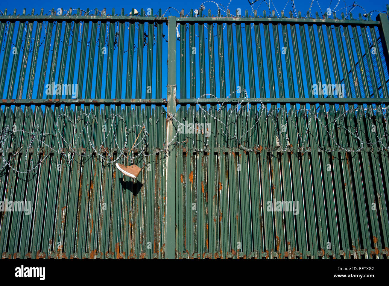 A shoe hangs on barb wire on a fence which makes up the peace wall ...