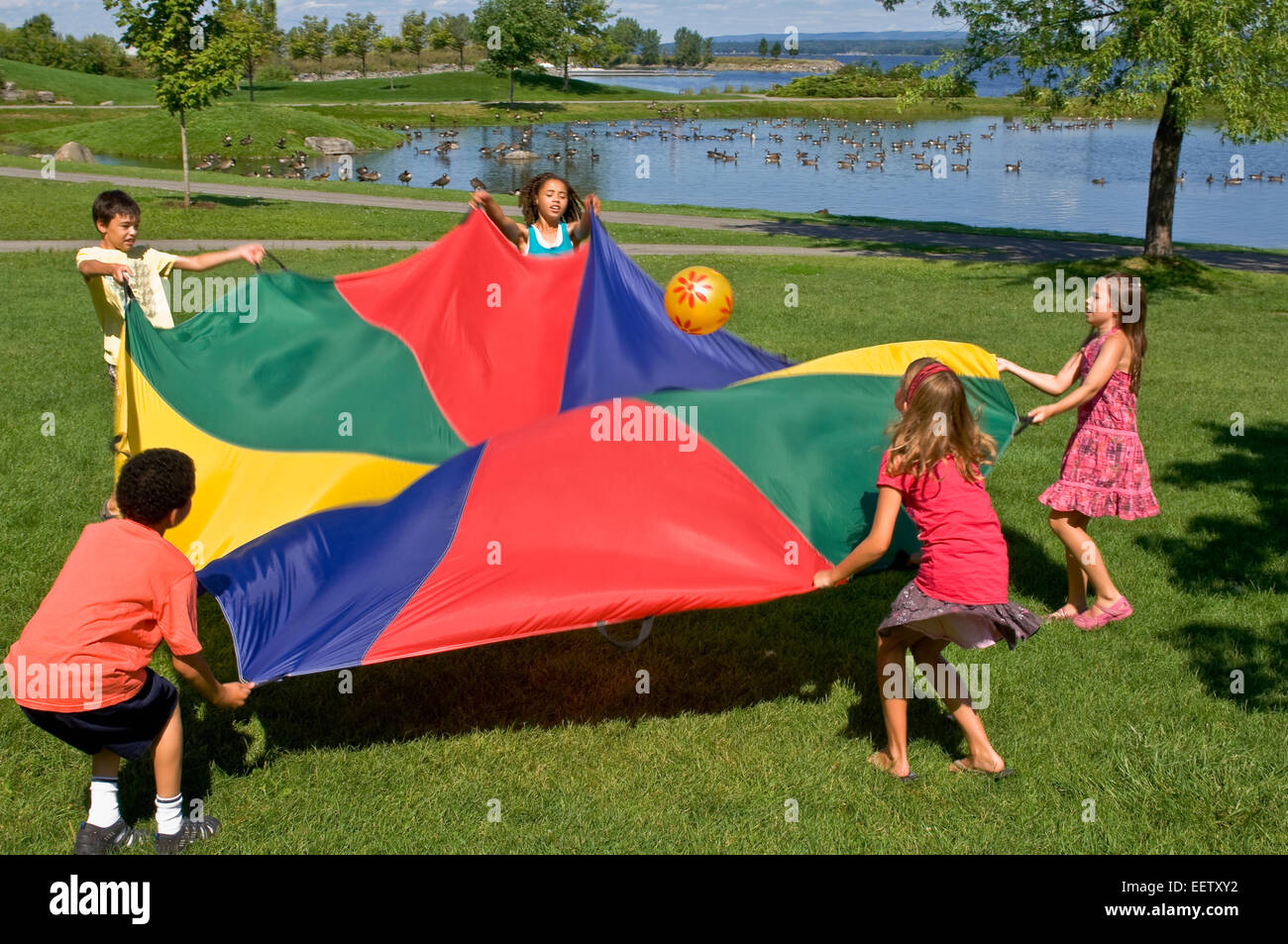 Children playing with a parachute Stock Photo - Alamy