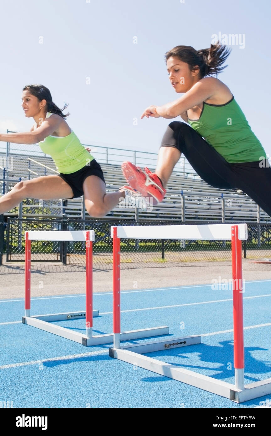 Two women jumping hurdles Stock Photo - Alamy