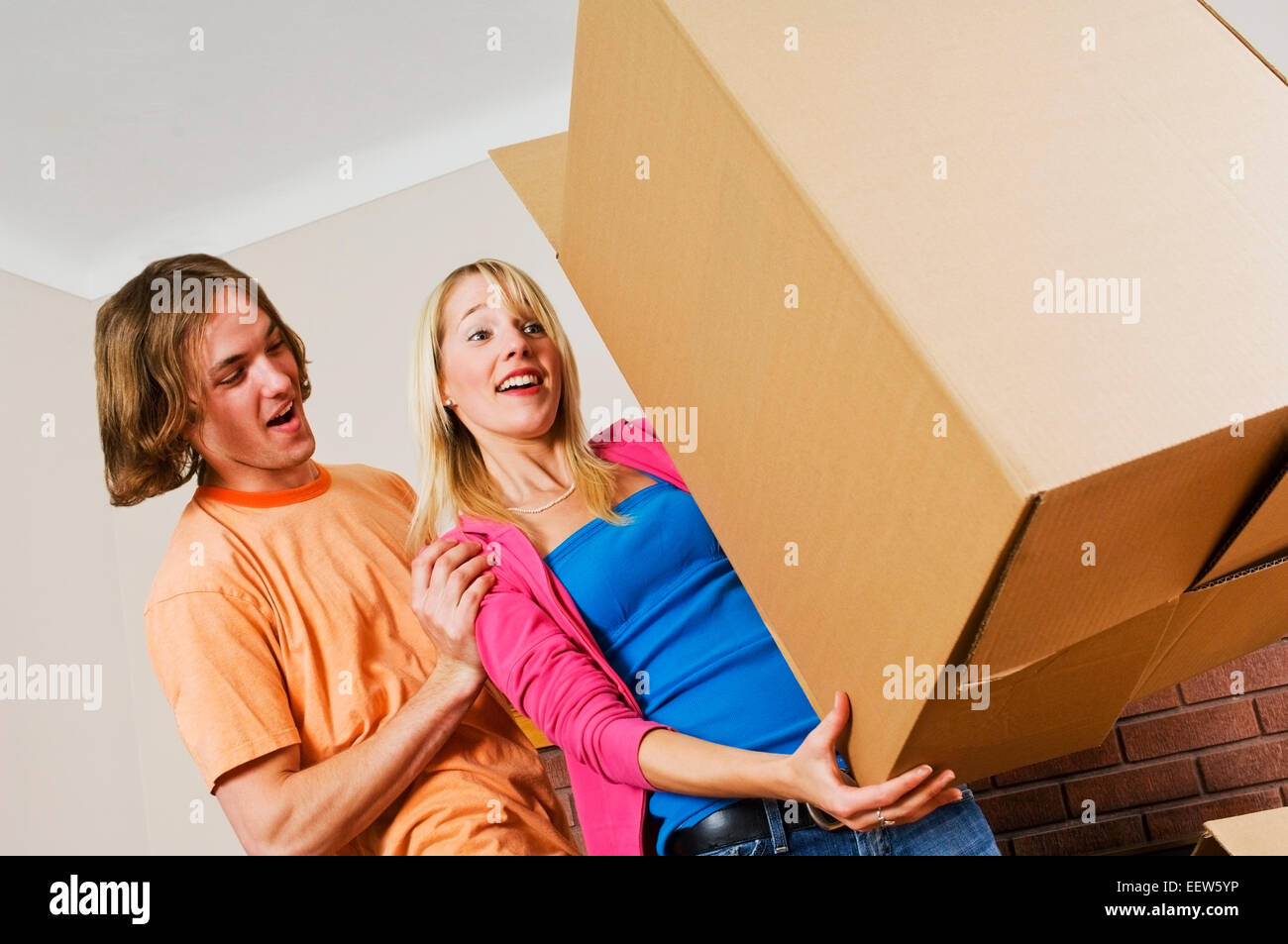 Young woman lifting a heavy box with young man supporting her Stock ...