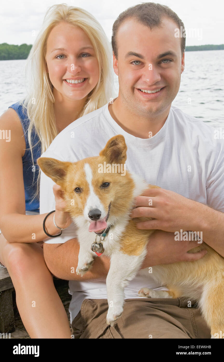 A couple sitting on a shoreline with their dog Stock Photo - Alamy