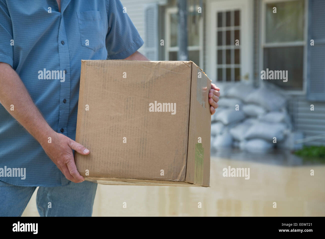Man carrying package during flood Stock Photo - Alamy