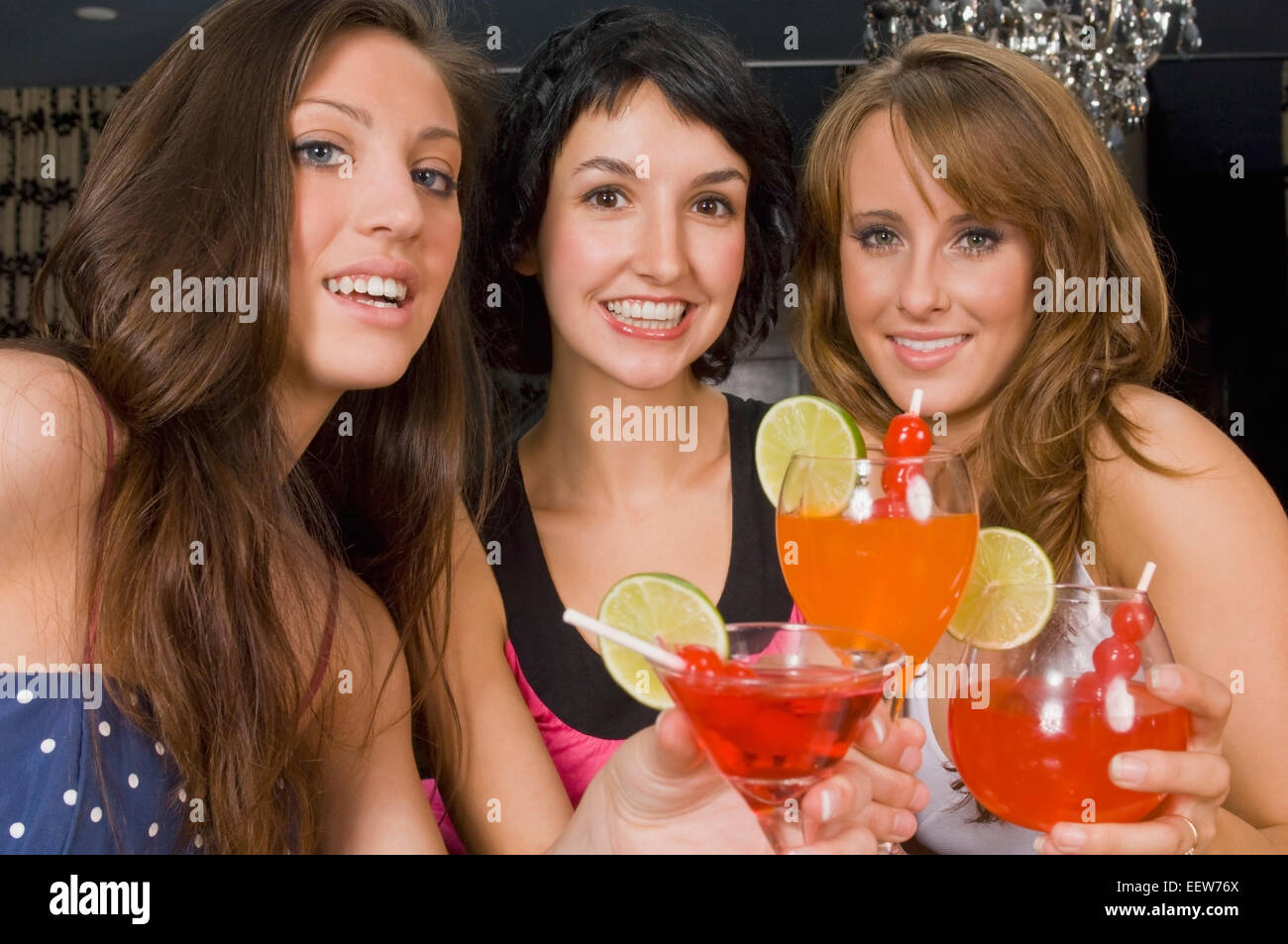 Three girls with cocktails in front of them Stock Photo - Alamy