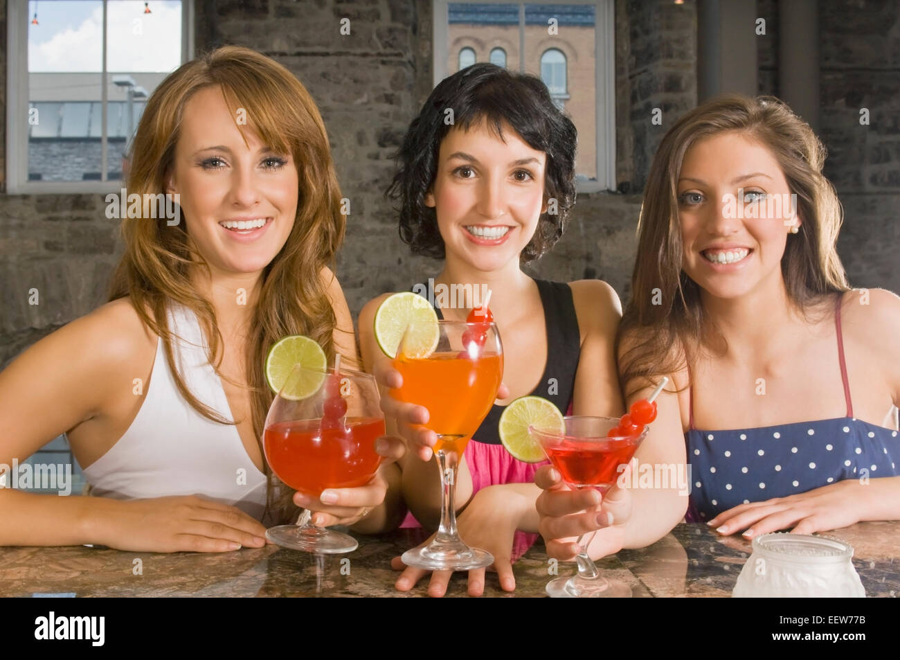 Three girl friends with cocktails Stock Photo - Alamy