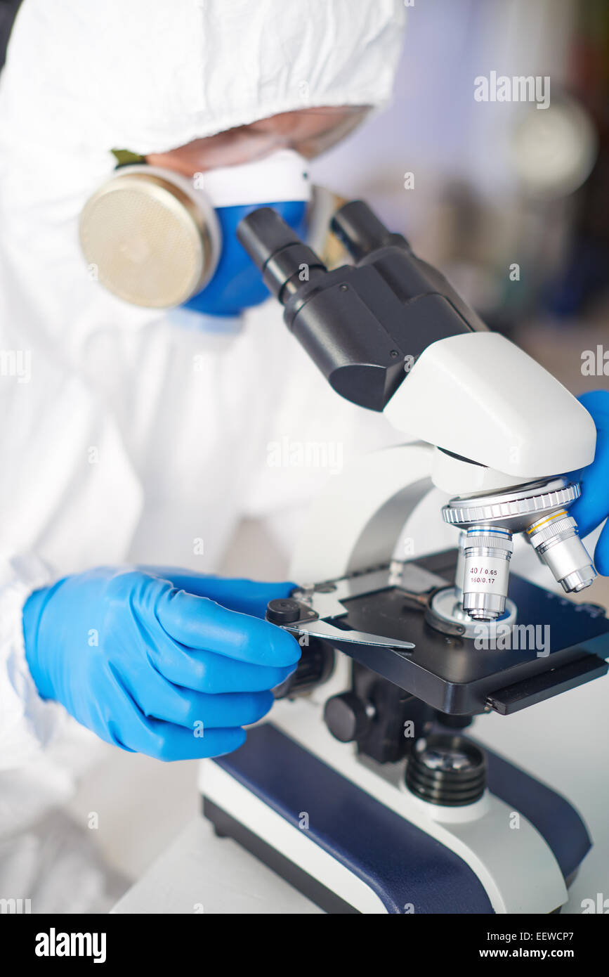 Male scientist in protective clothing looking in microscope Stock Photo ...