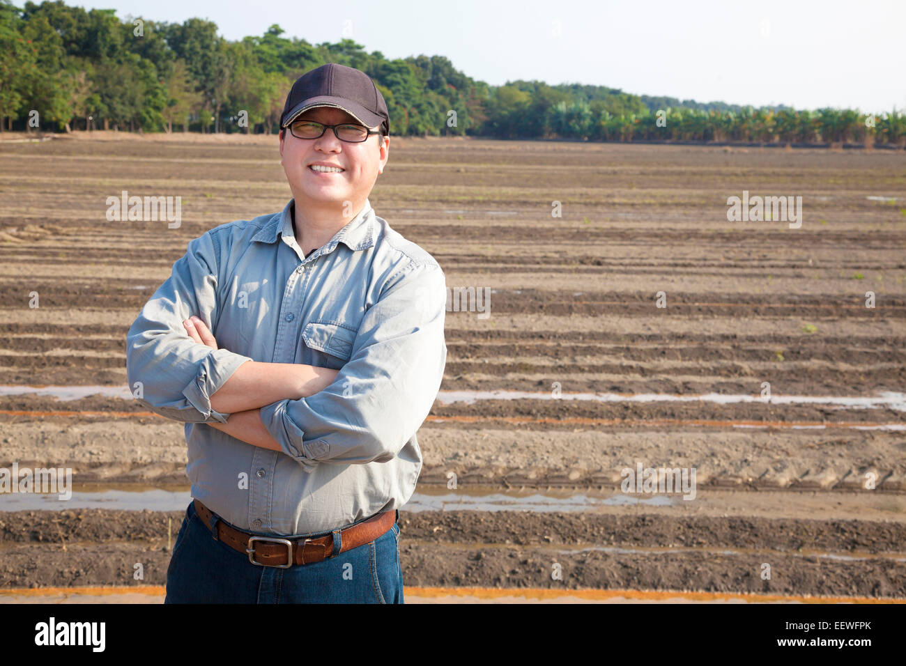 Farmer man standing on farming land Stock Photo - Alamy