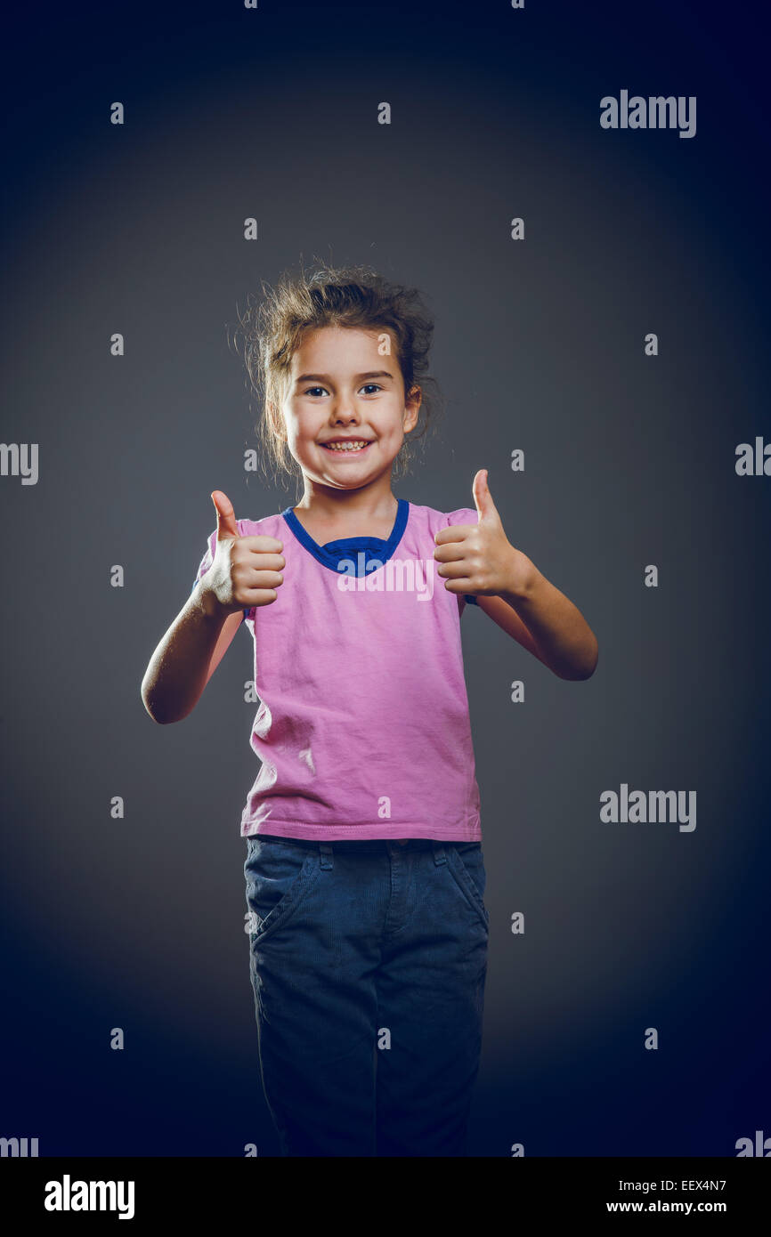 the girl child is showing thumbs up gesture yes on a gray backgr Stock ...