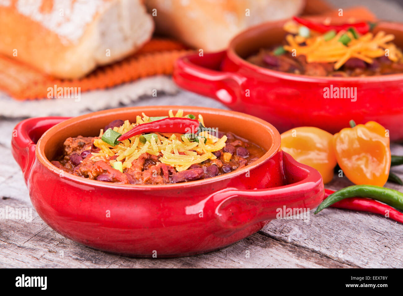 Ceramic crock of meat and bean chili garnished with shredded cheddar ...