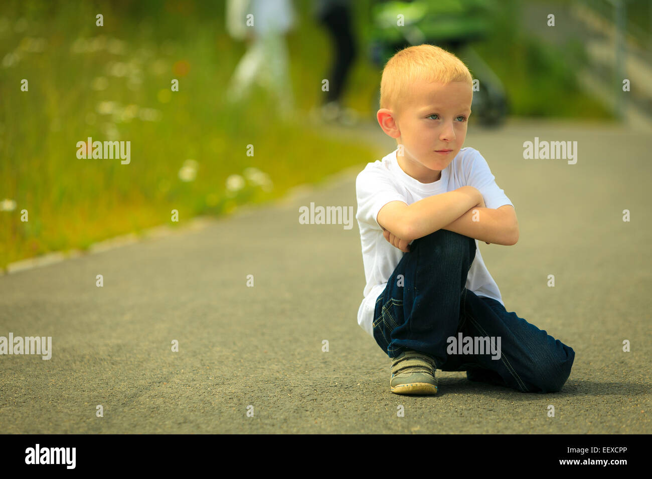Portrait of thoughtful, pensive little boy child or kid in summer park ...