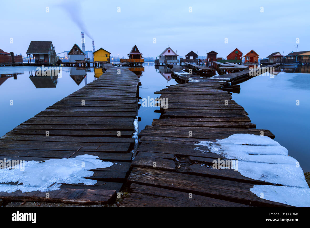 Sunset lake Bokod with pier and fishing wooden cottages, power plant in ...