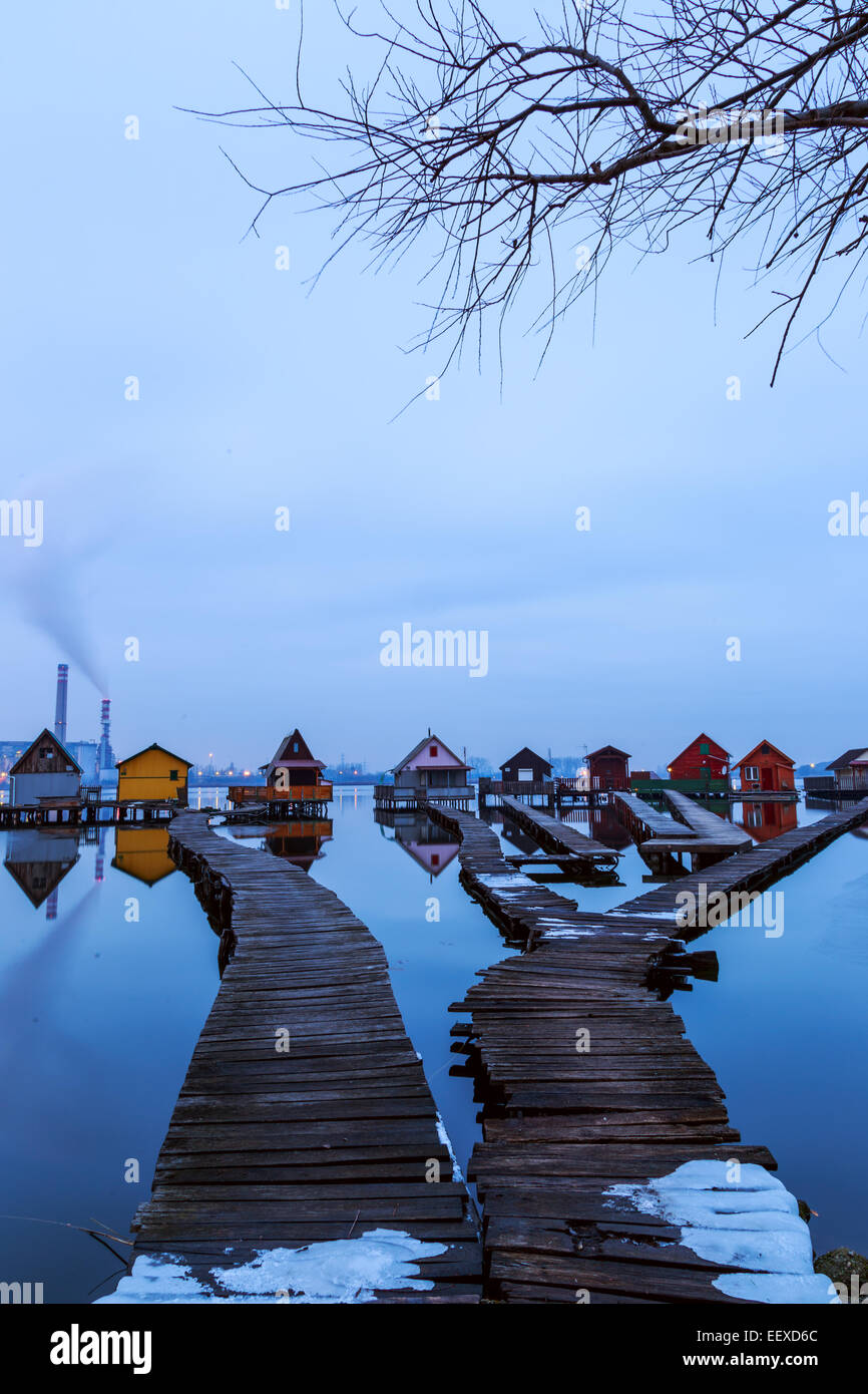 Sunset lake Bokod with pier and fishing wooden cottages, power plant in ...