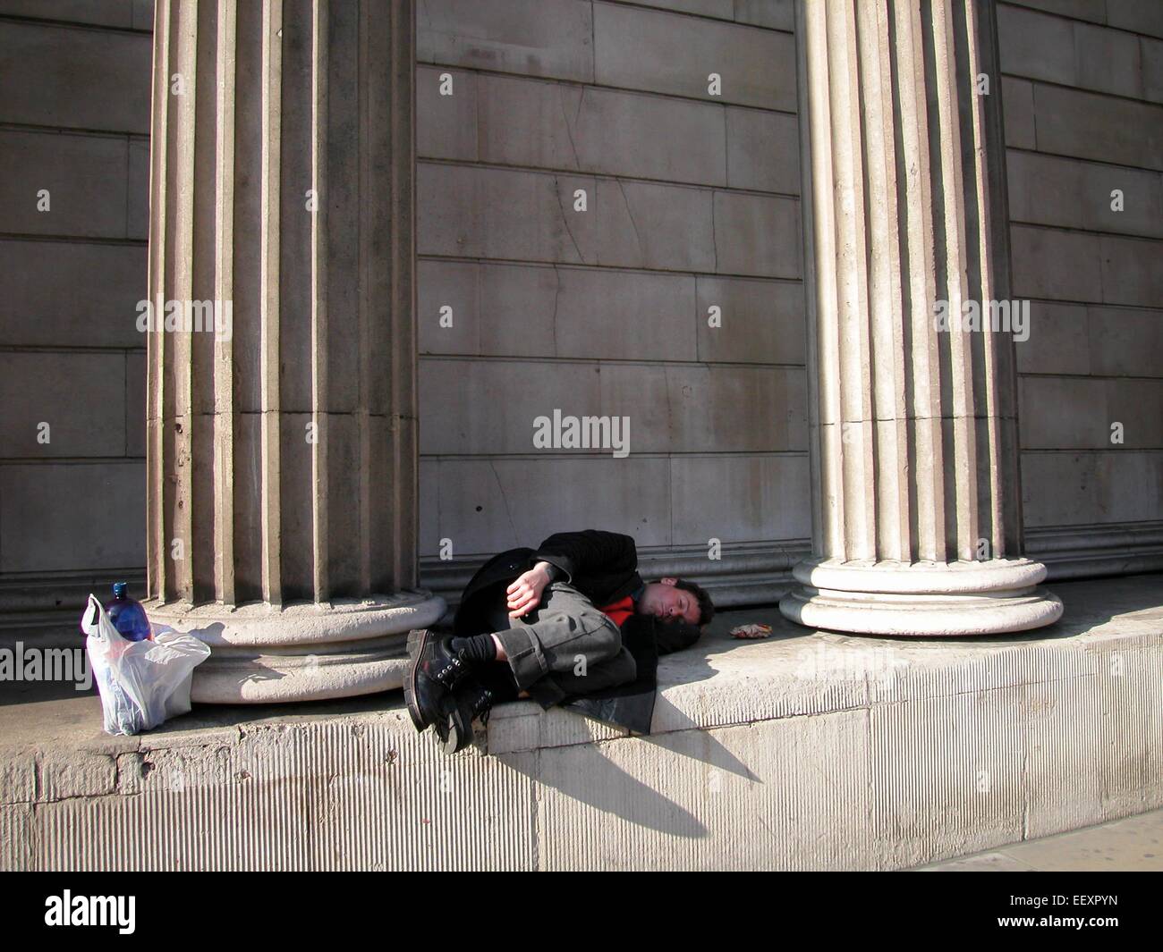 Vagrant homeless man sleeping rough beneath the stone pillars of the ...