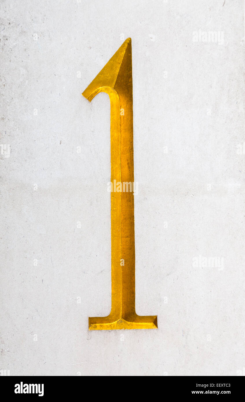 Golden number one on stone wall Stock Photo - Alamy