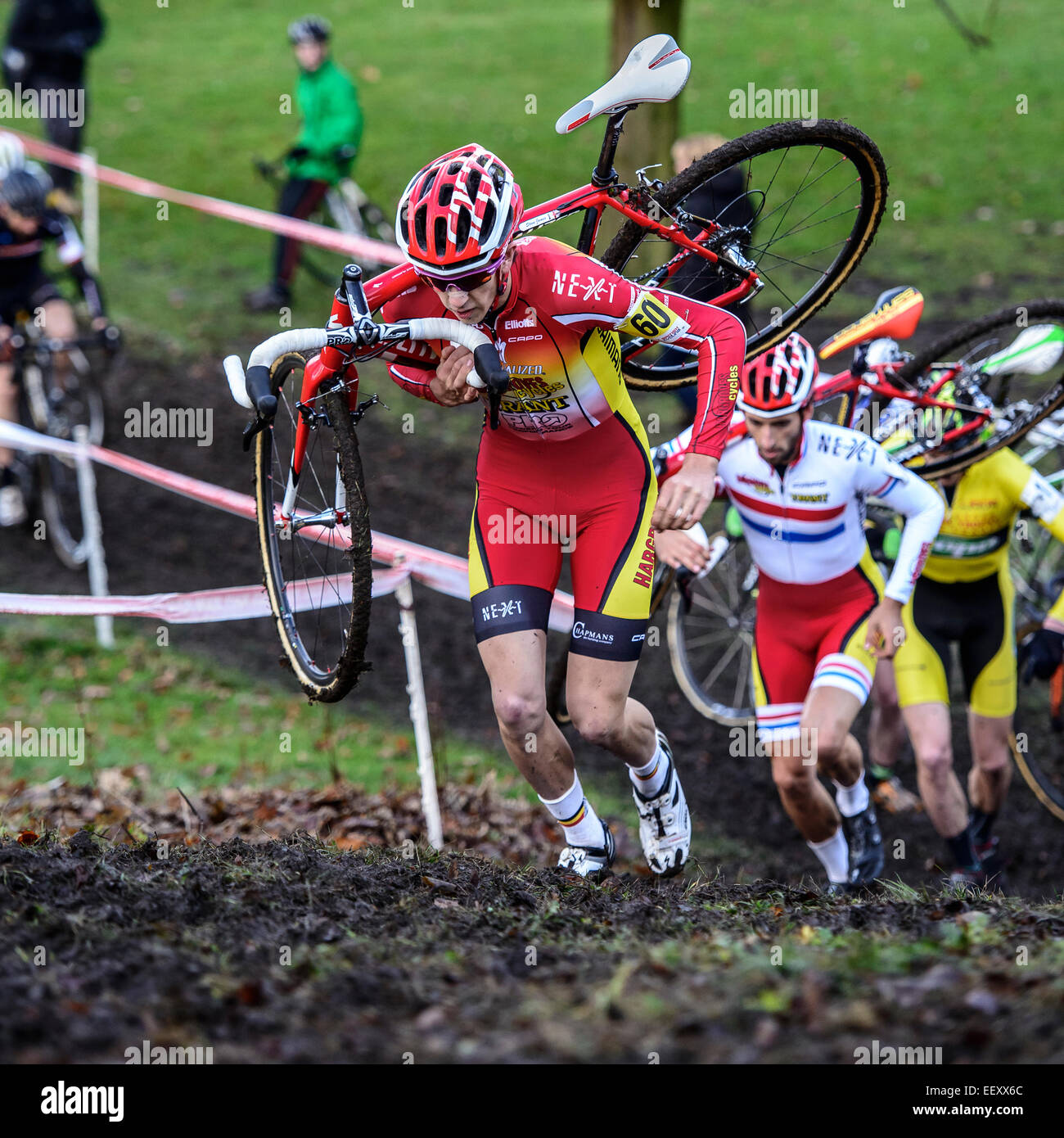 Competitors in a cyclo-cross race carry their bikes up a steep muddy ...