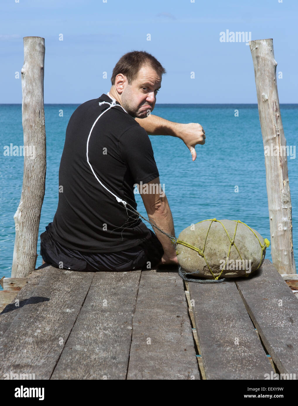 A man sits on a pier with a noose around his neck Stock Photo - Alamy