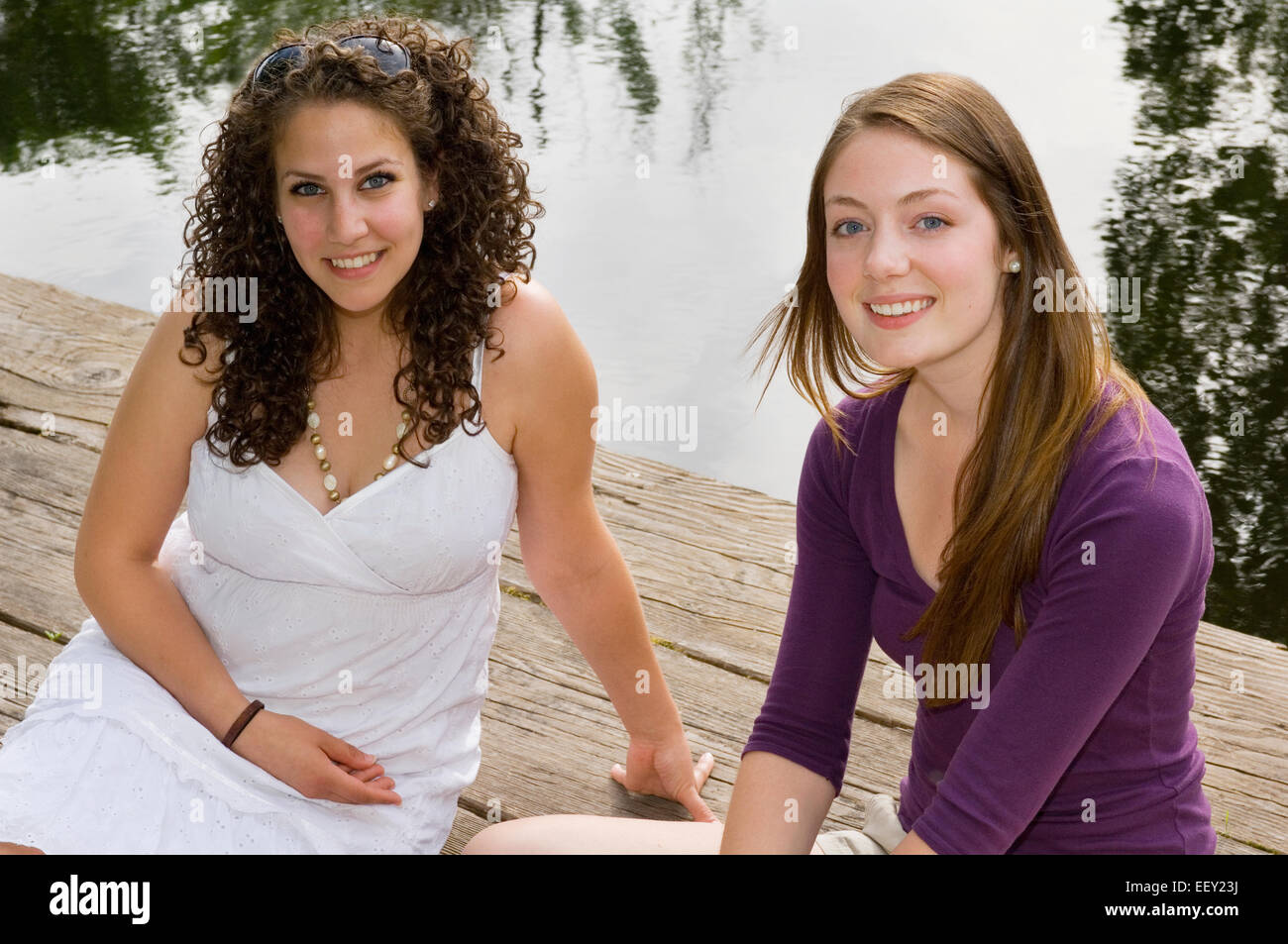 Two friends sitting on a dock Stock Photo - Alamy