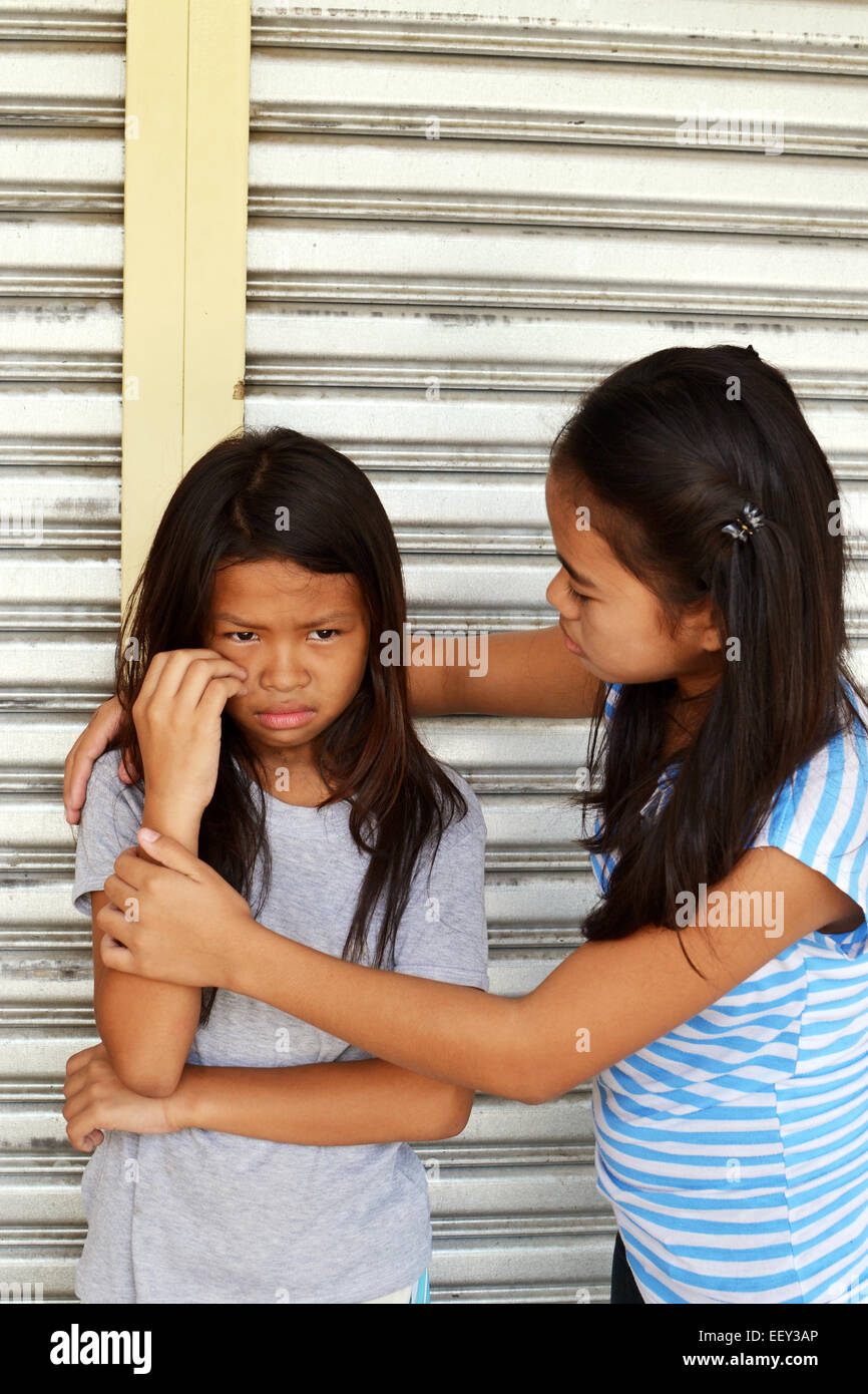 A young lady comforting a poor crying homeless child in the street ...