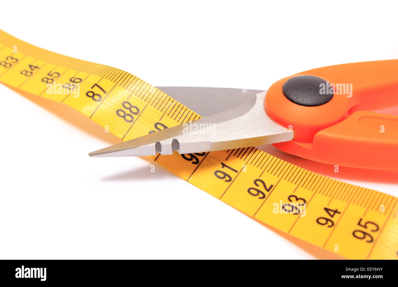 Orange scissors cutting tape measure on white background, concept for ...