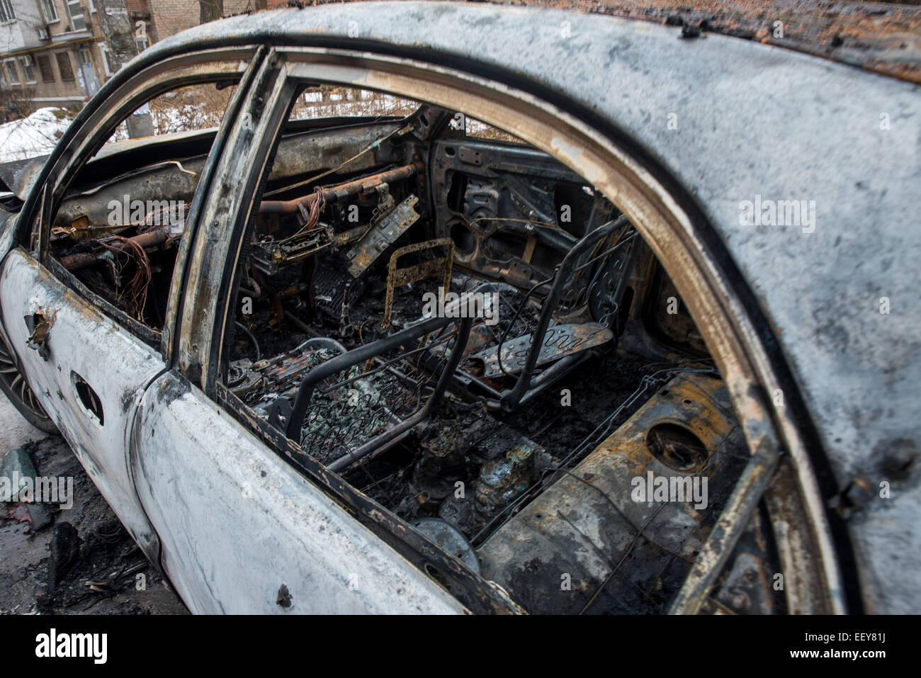 The ruins of a car sit in the driveway of an apartment block bombarded ...