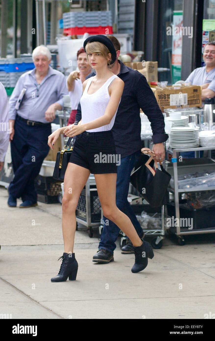 Taylor Swift showing a lot of skin in shorts and a white tank top while ...