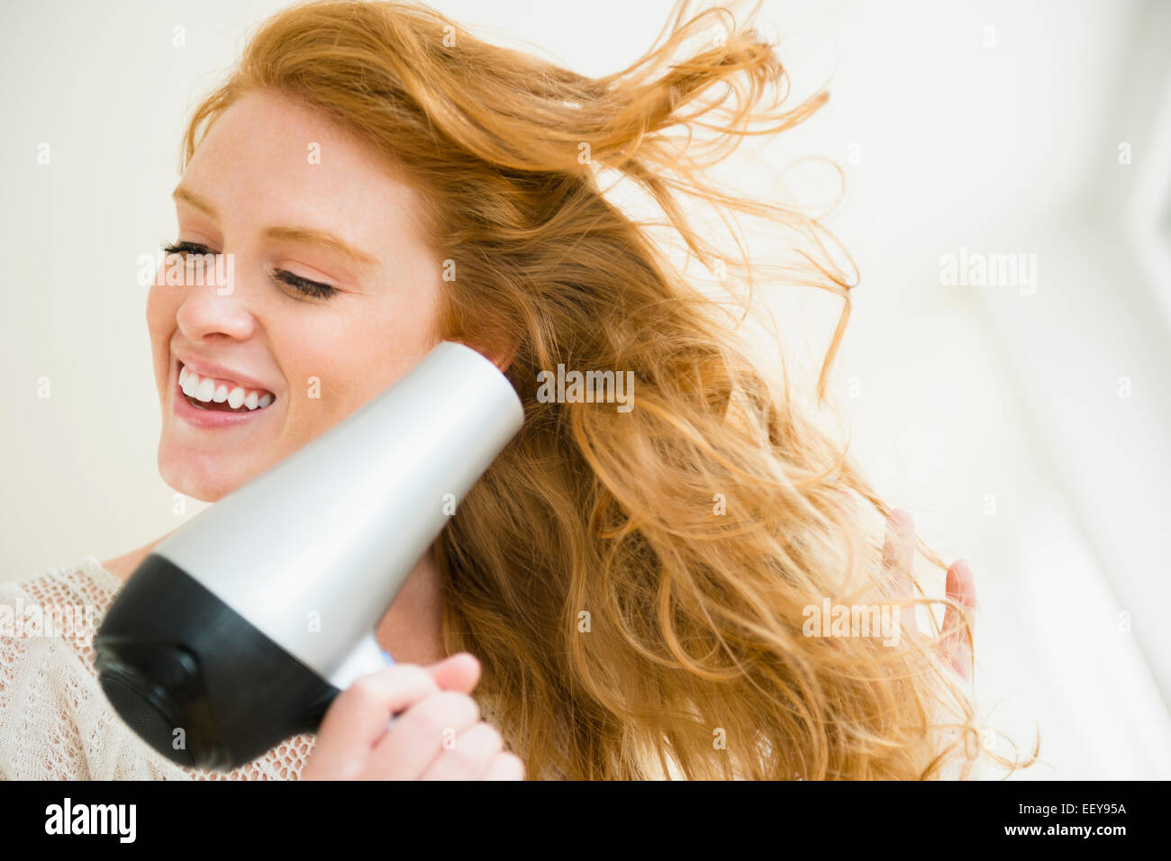 Woman blow drying hair Stock Photo - Alamy