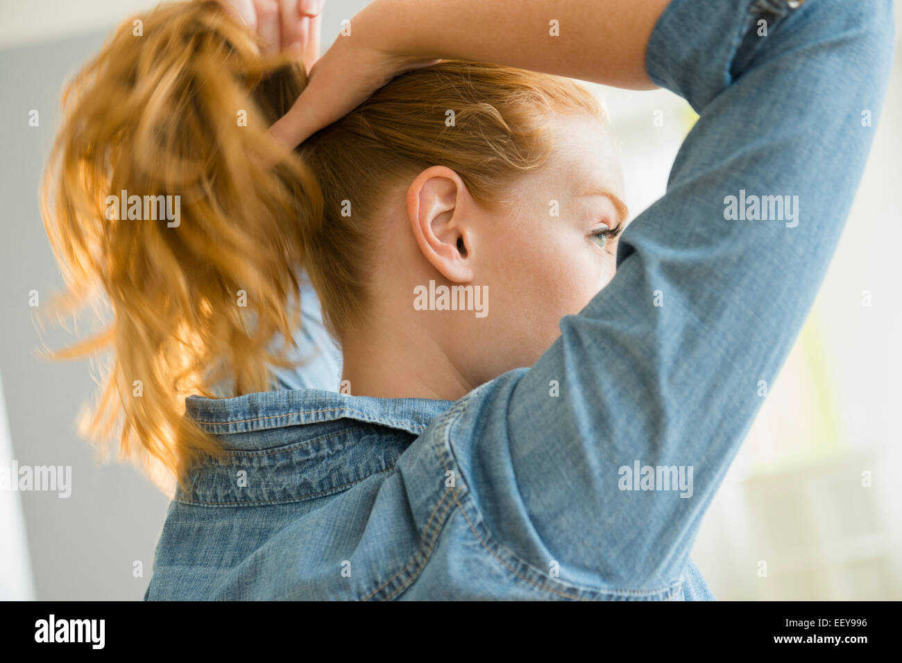 Young woman tying hair Stock Photo - Alamy