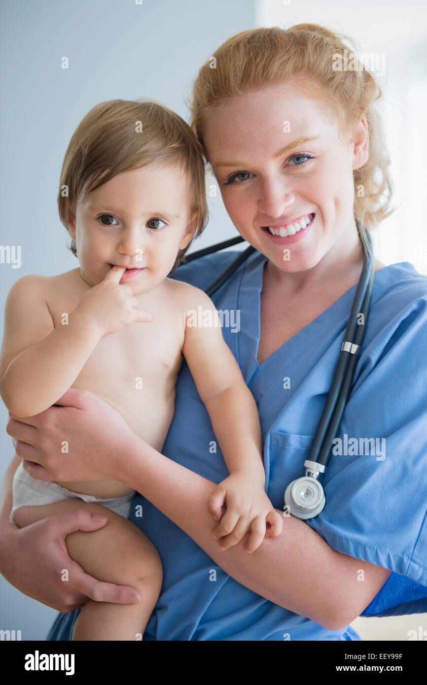 Portrait of female nurse carrying baby boy (12-17 months Stock Photo ...