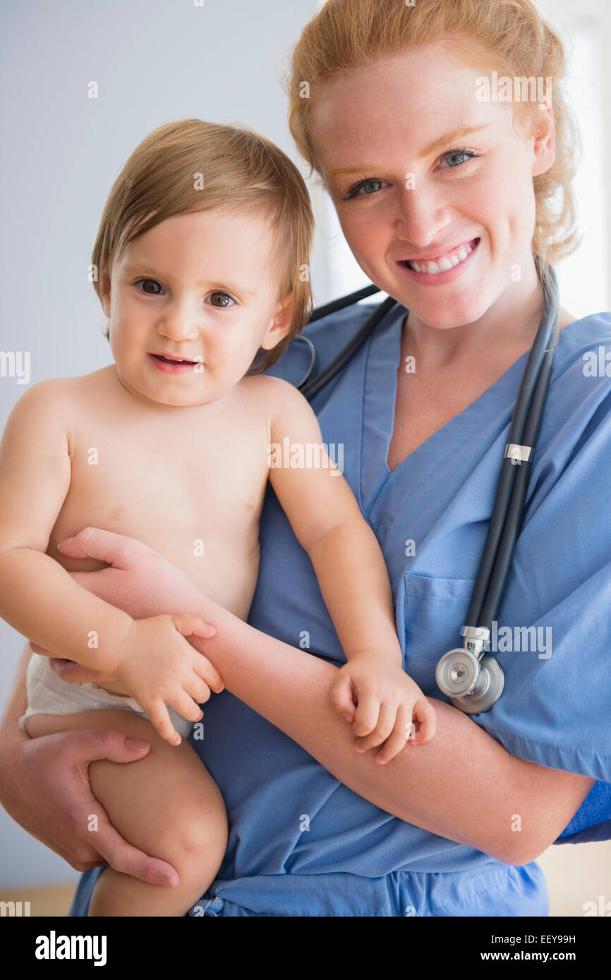 Portrait of female nurse carrying baby boy (12-17 months Stock Photo ...