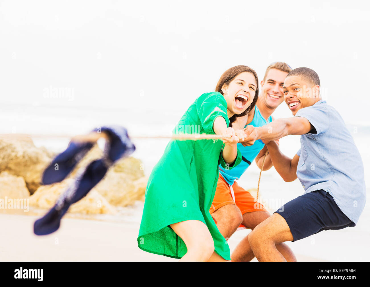 Young people pulling rope on beach Stock Photo - Alamy