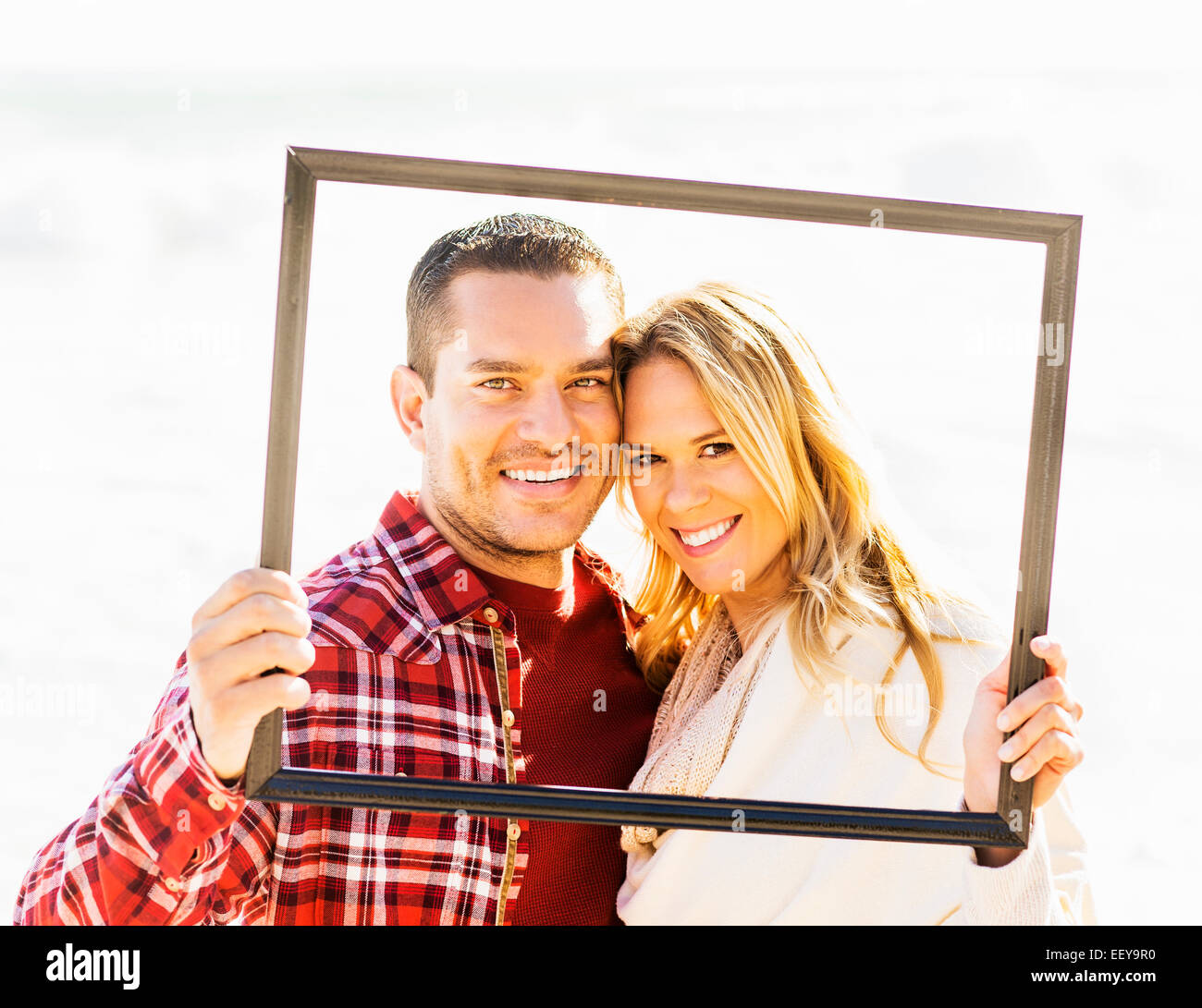 Portrait of couple holding frame Stock Photo - Alamy