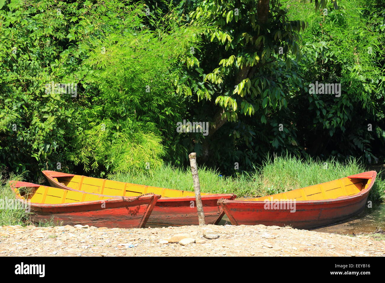 Red-yellow-orange colored wooden rowboats stranded on the shore of the ...