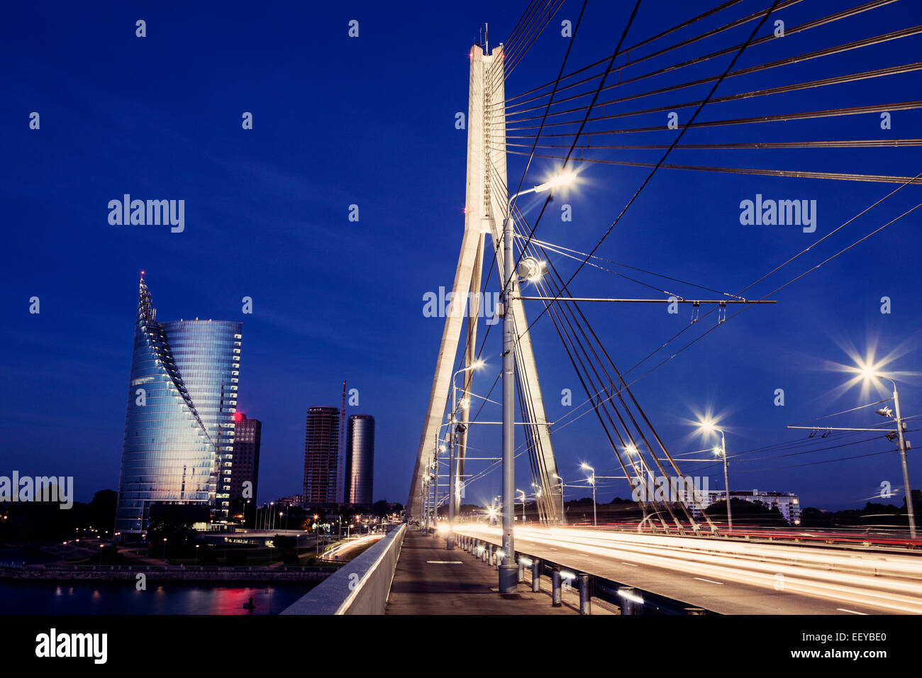 Latvia, Riga, Suspension bridge with skyscrapers on background at night ...