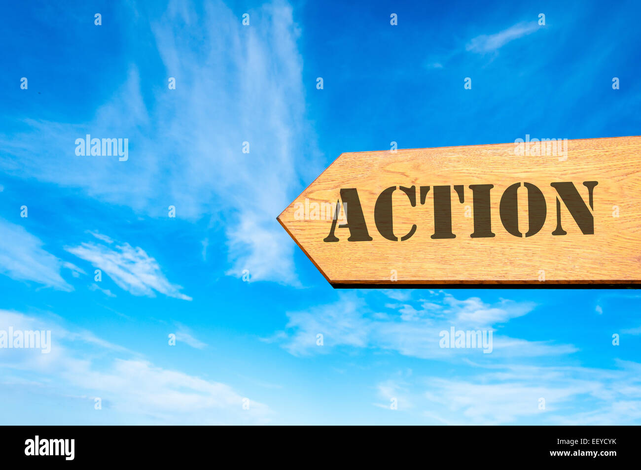 Wood arrow sign against clear blue sky with Action message Stock Photo ...