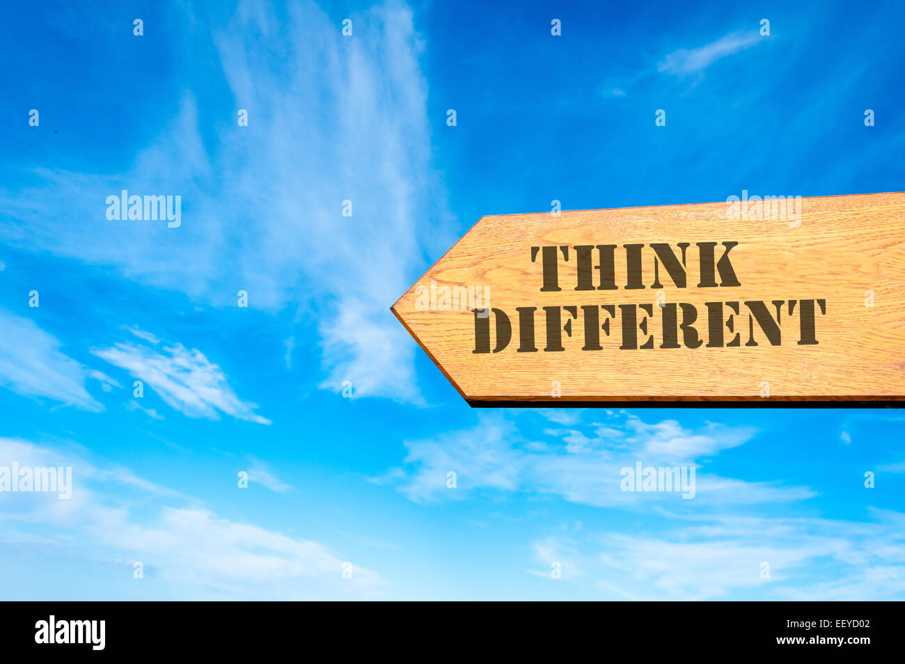 Wood arrow sign against clear blue sky with Think Different message ...