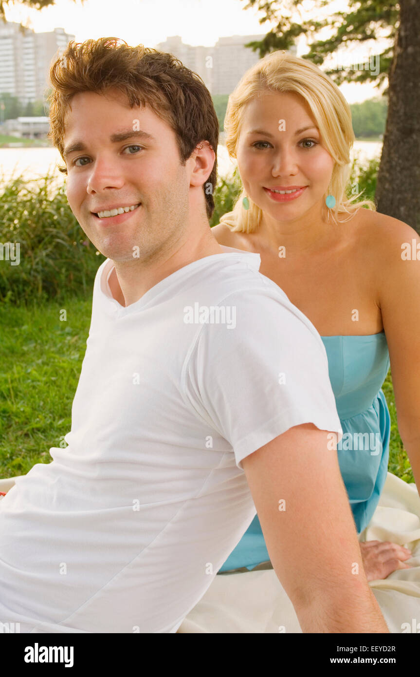 Couple sitting by water's edge Stock Photo - Alamy