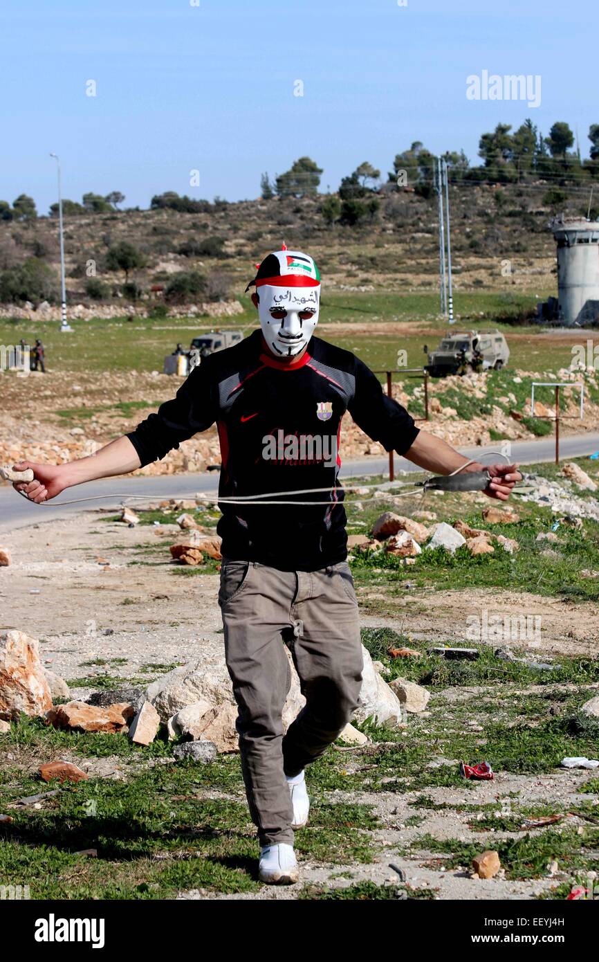A masked Palestinian youth has a home-made slingshot in his hand as he ...