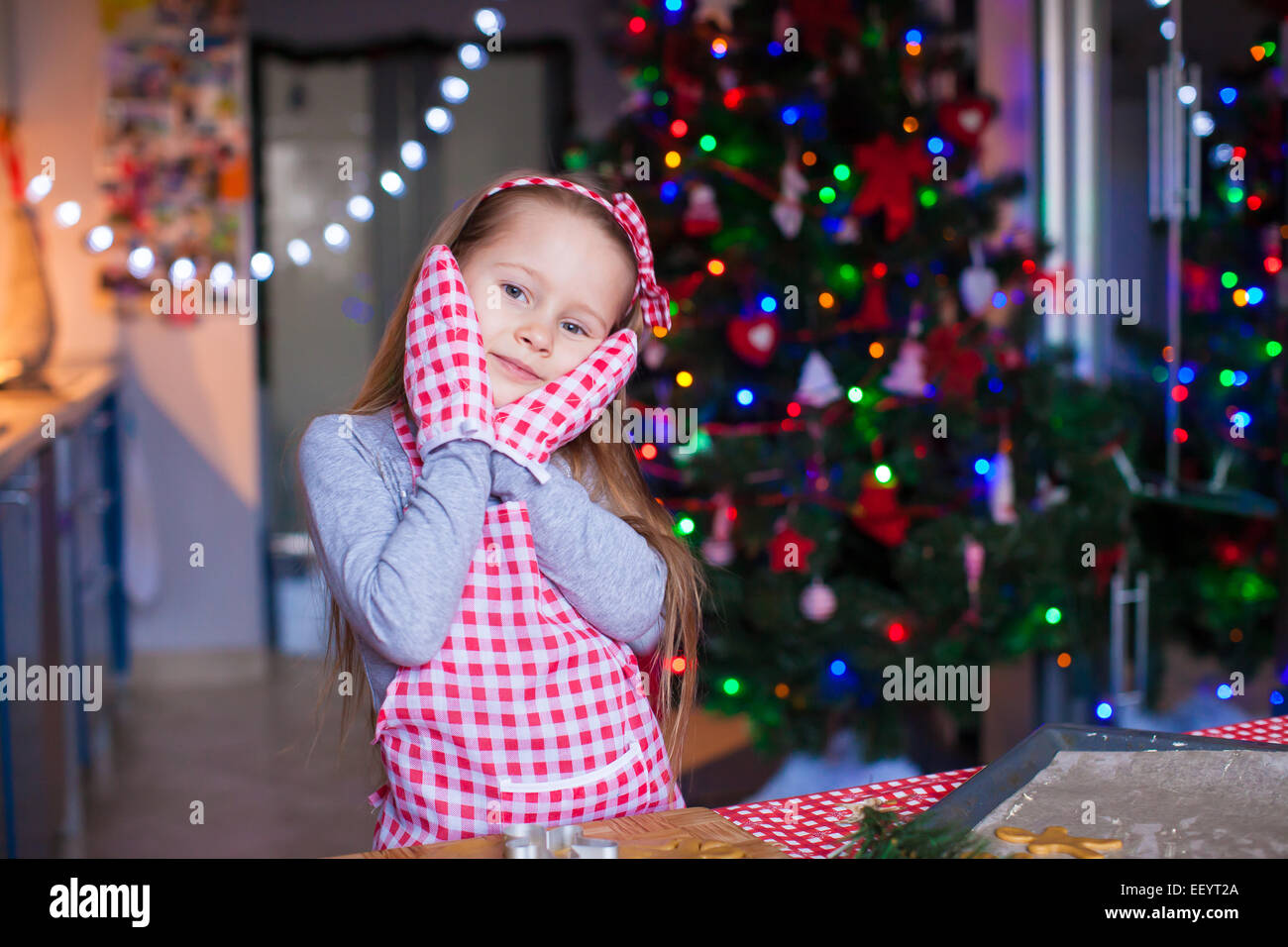 Adorable little girl in mittens baking Christmas gingerbread cookies ...