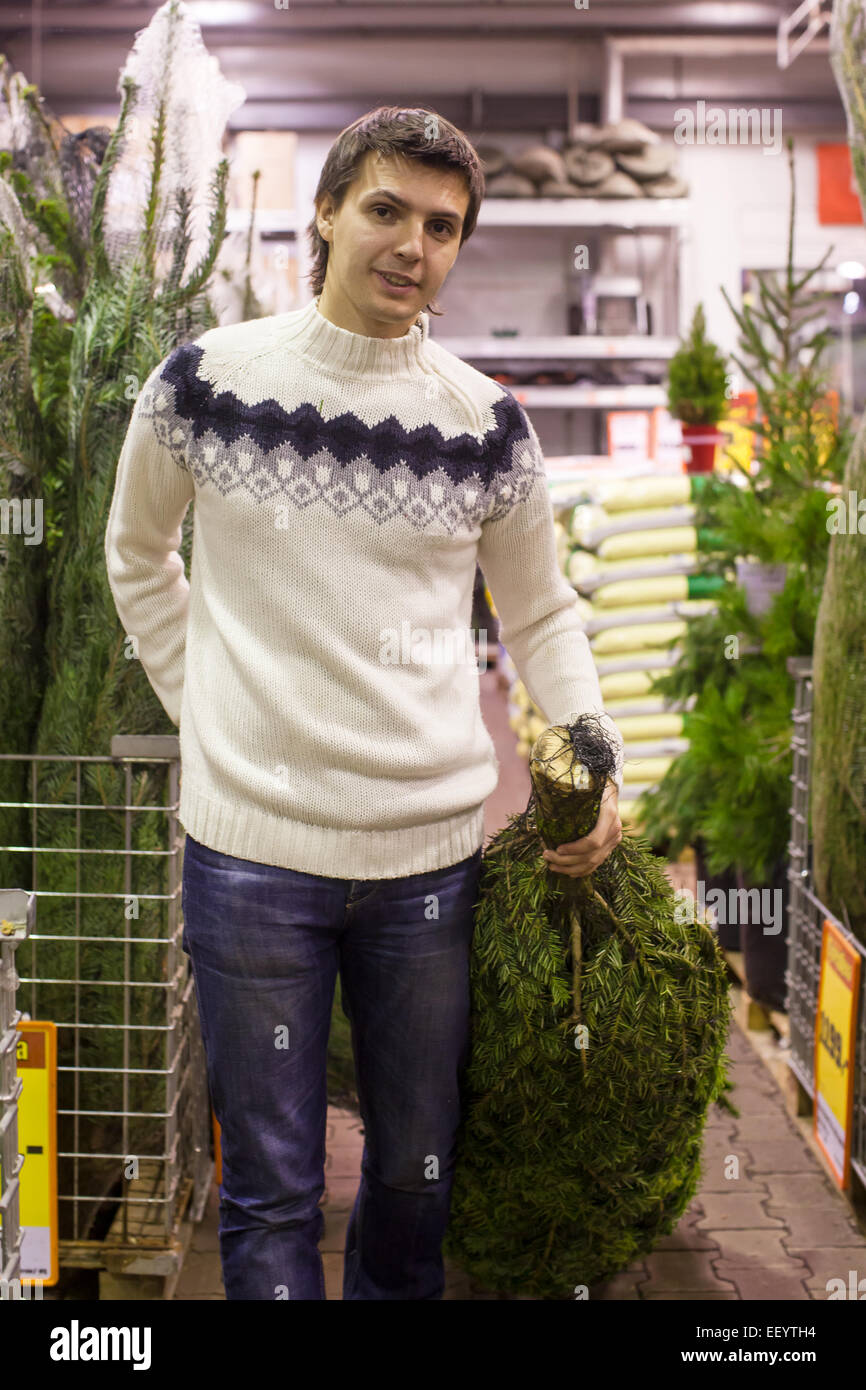 Young man buying green Christmas tree in big market Stock Photo - Alamy